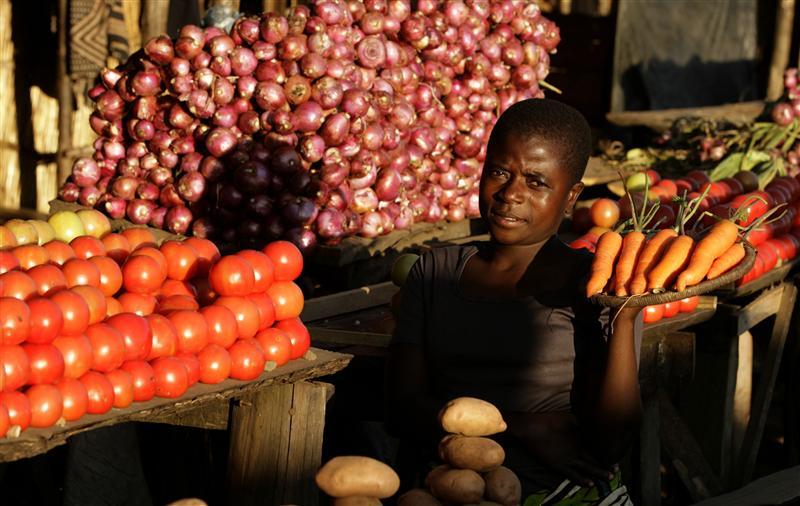 A girl poses for a photographer at her vegetable stall in Tsangano ...